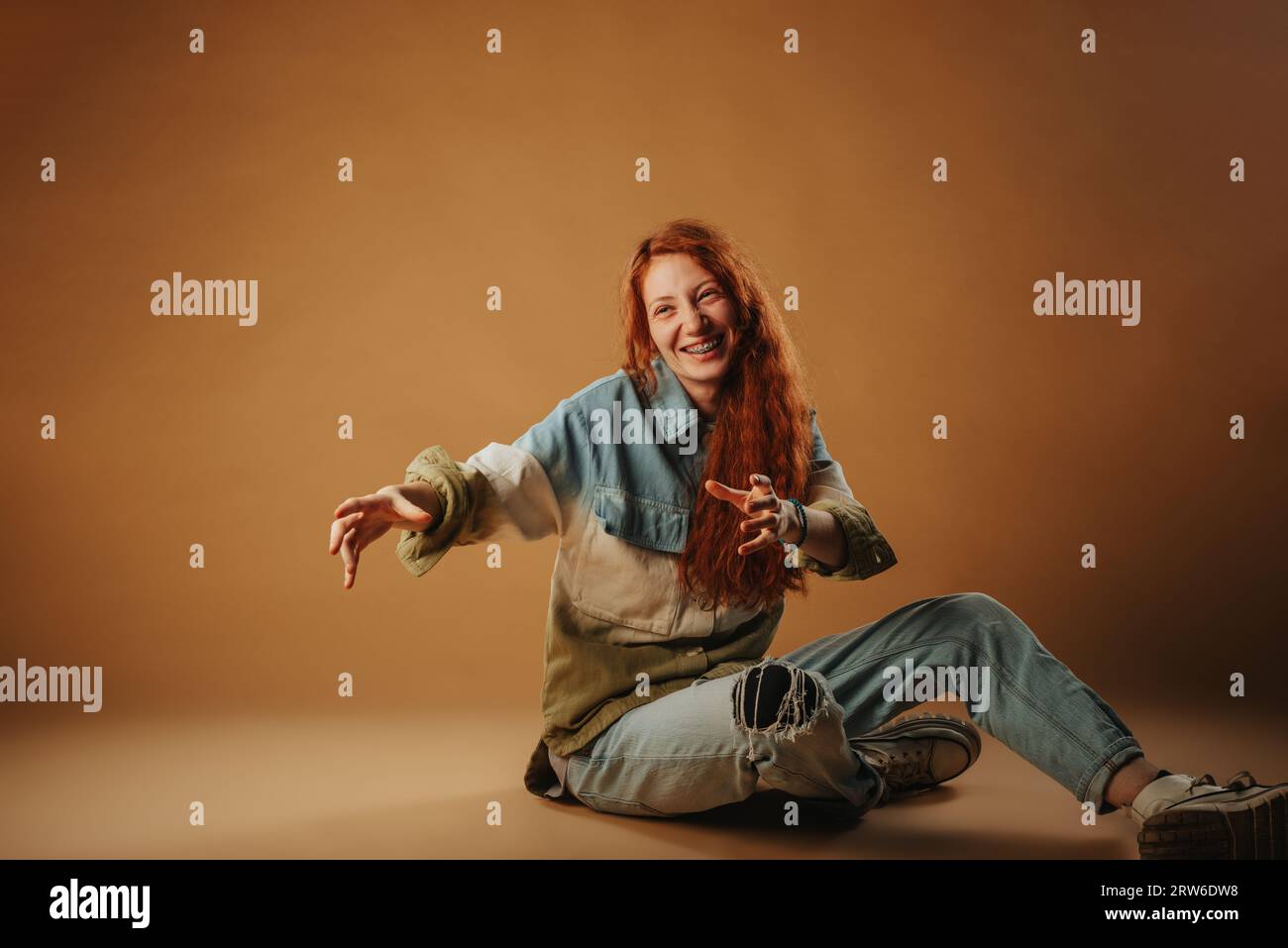 Cute ginger girl with braces smiling while sitting at the studio on a ...