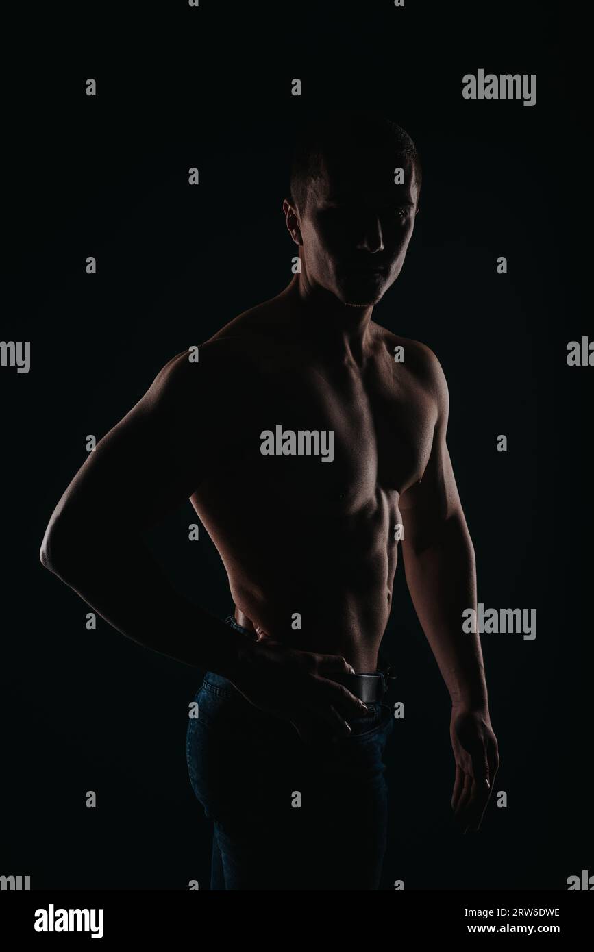 Stunning and well-built man standing in a dark room and posing Stock ...