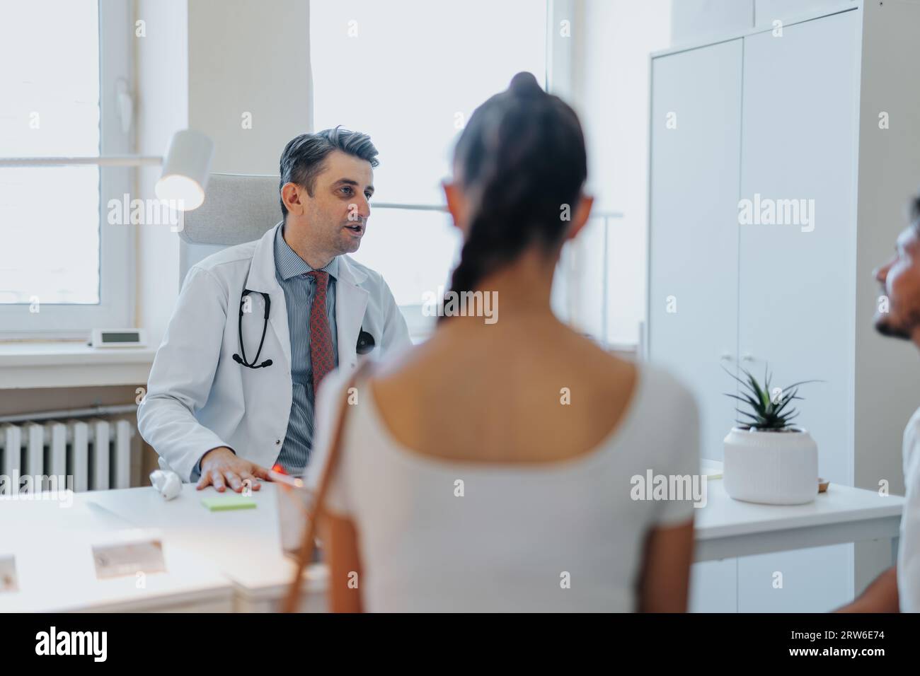 A couple consults a doctor in an office, discussing health problems and ...