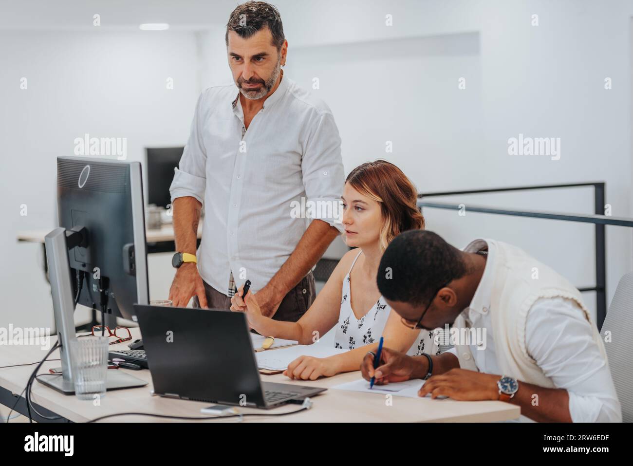 Business partners in a diverse, creative office work together using ...