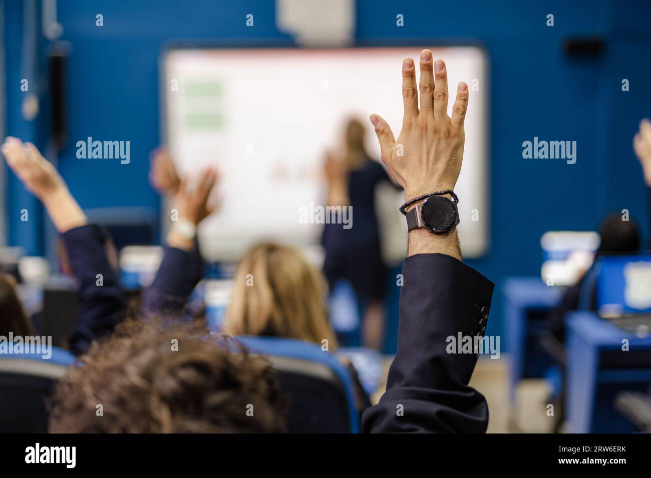 College students raising hands for answering after their professor ...