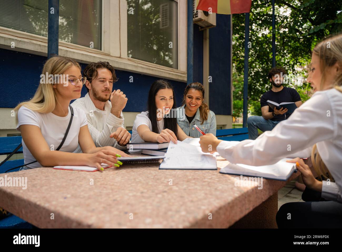 A diverse group of university students gathered outdoors, collaborating ...