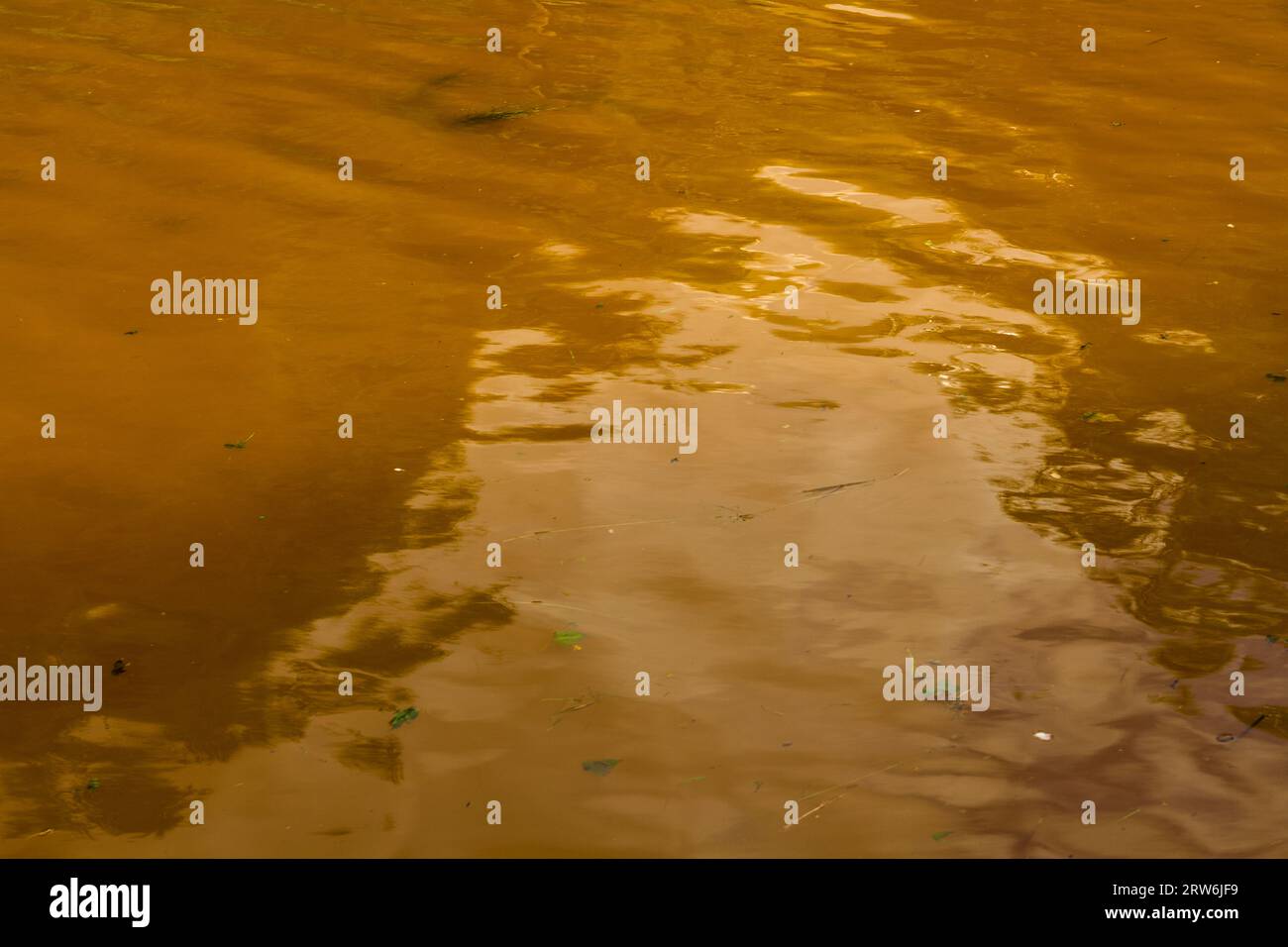 Surface of orange yellow water coloured by clay Stock Photo - Alamy