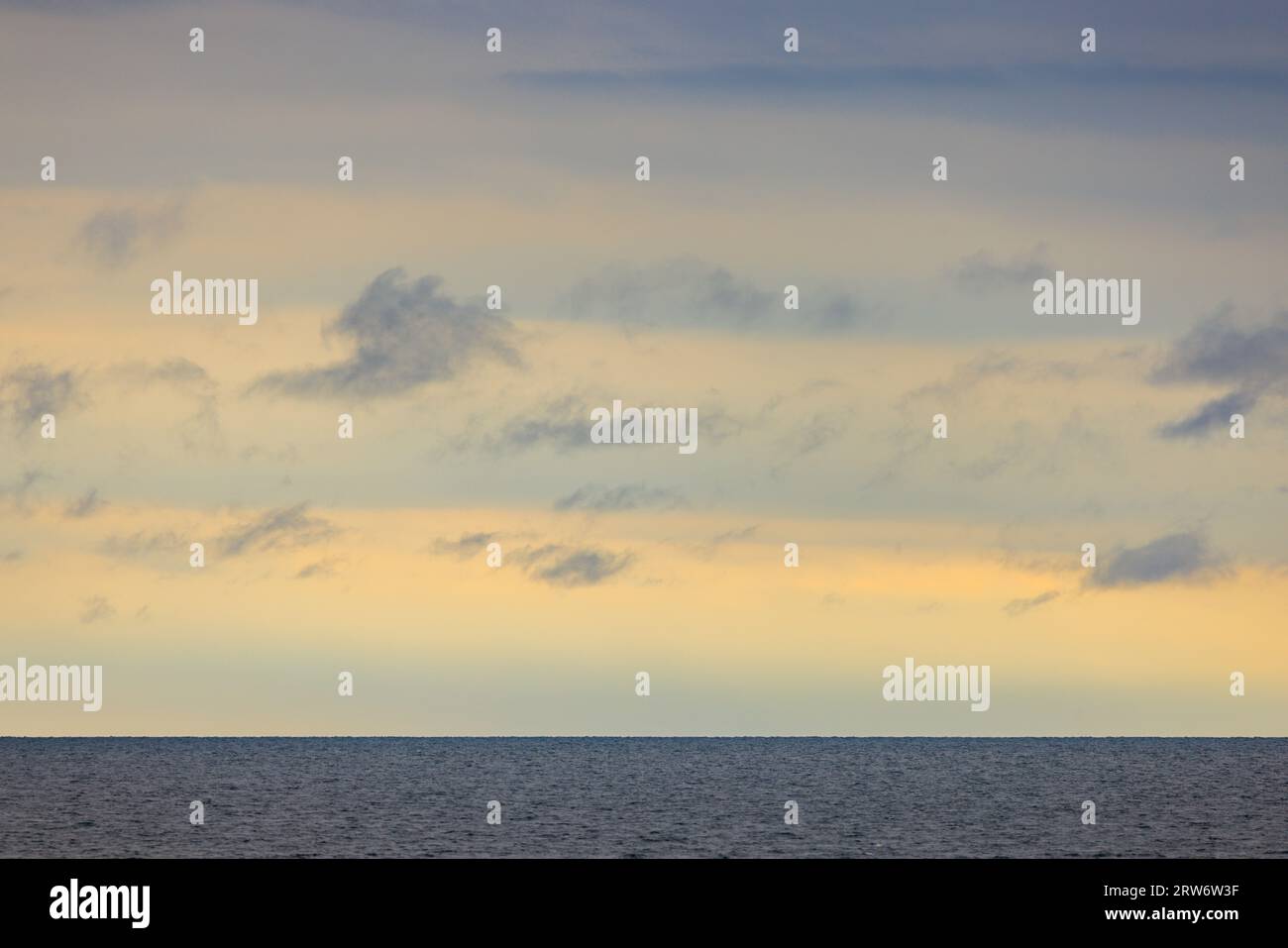Distant horizon between cloud layer and calm seas at sunrise Stock ...