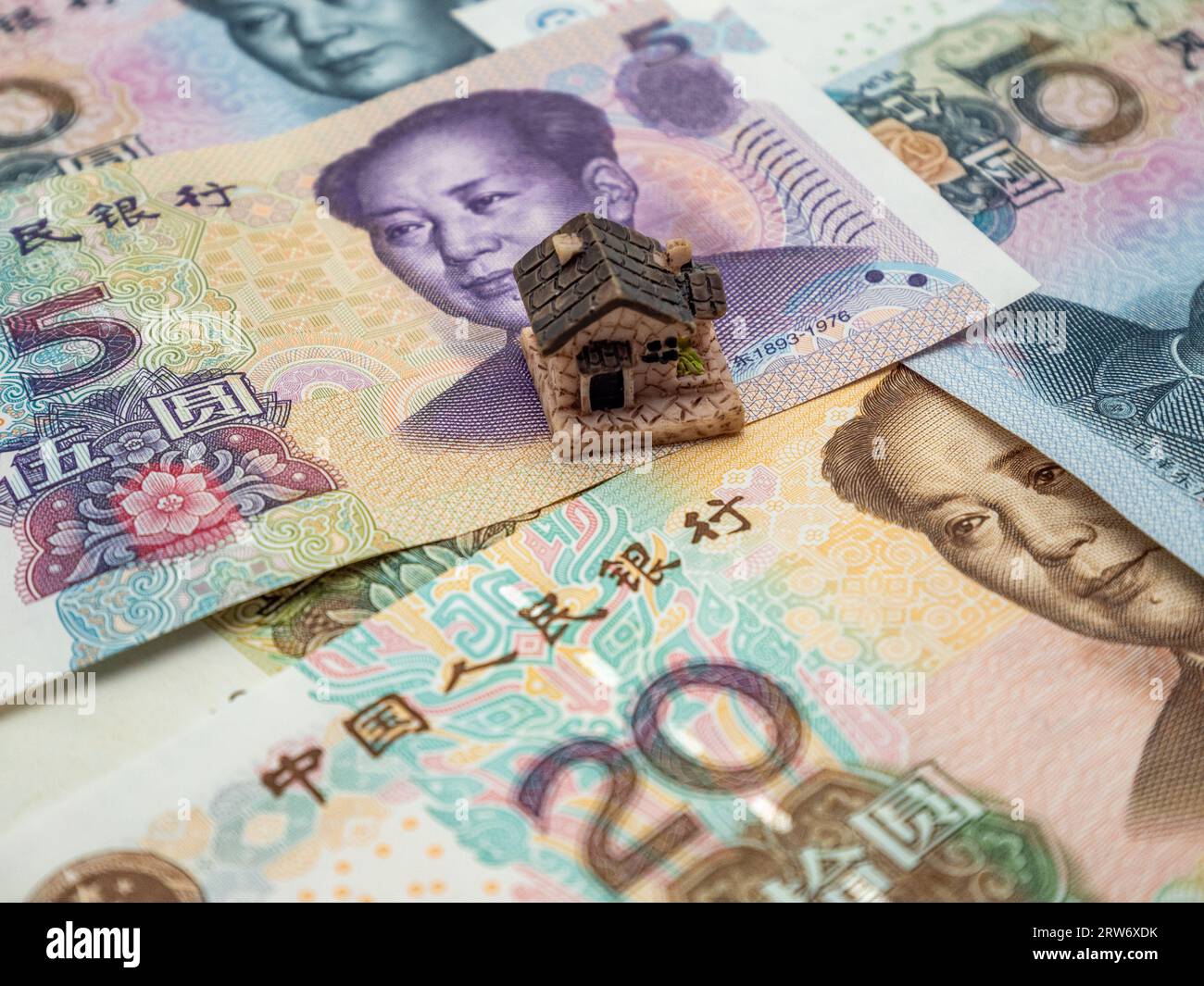 A stack of Chinese Yuan banknotes with a small miniature house on them ...