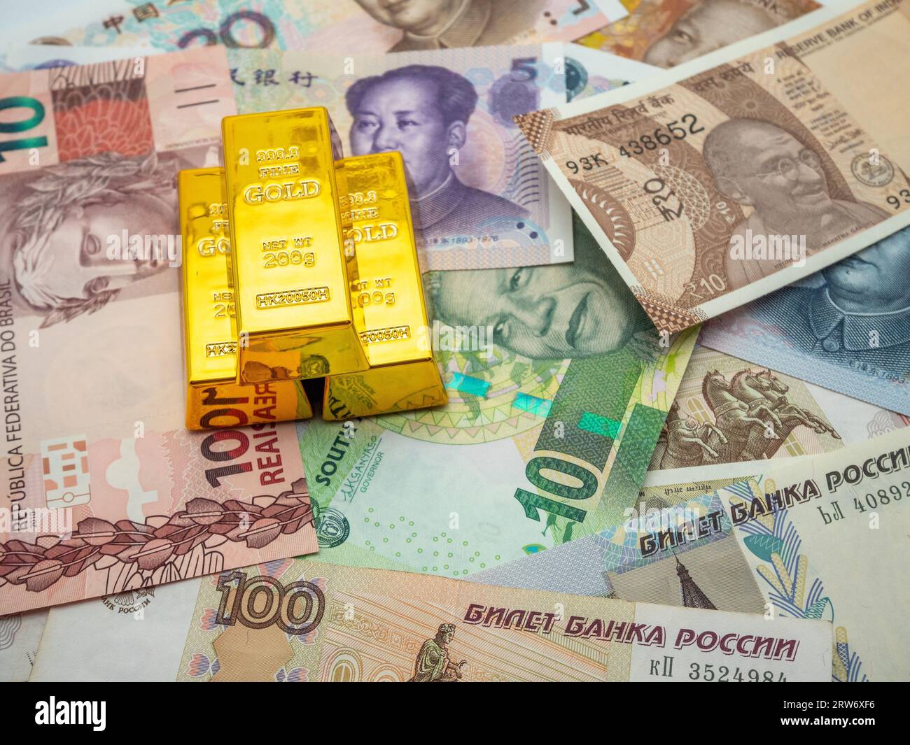 A close-up image of gold bullion bars with various banknotes of ...