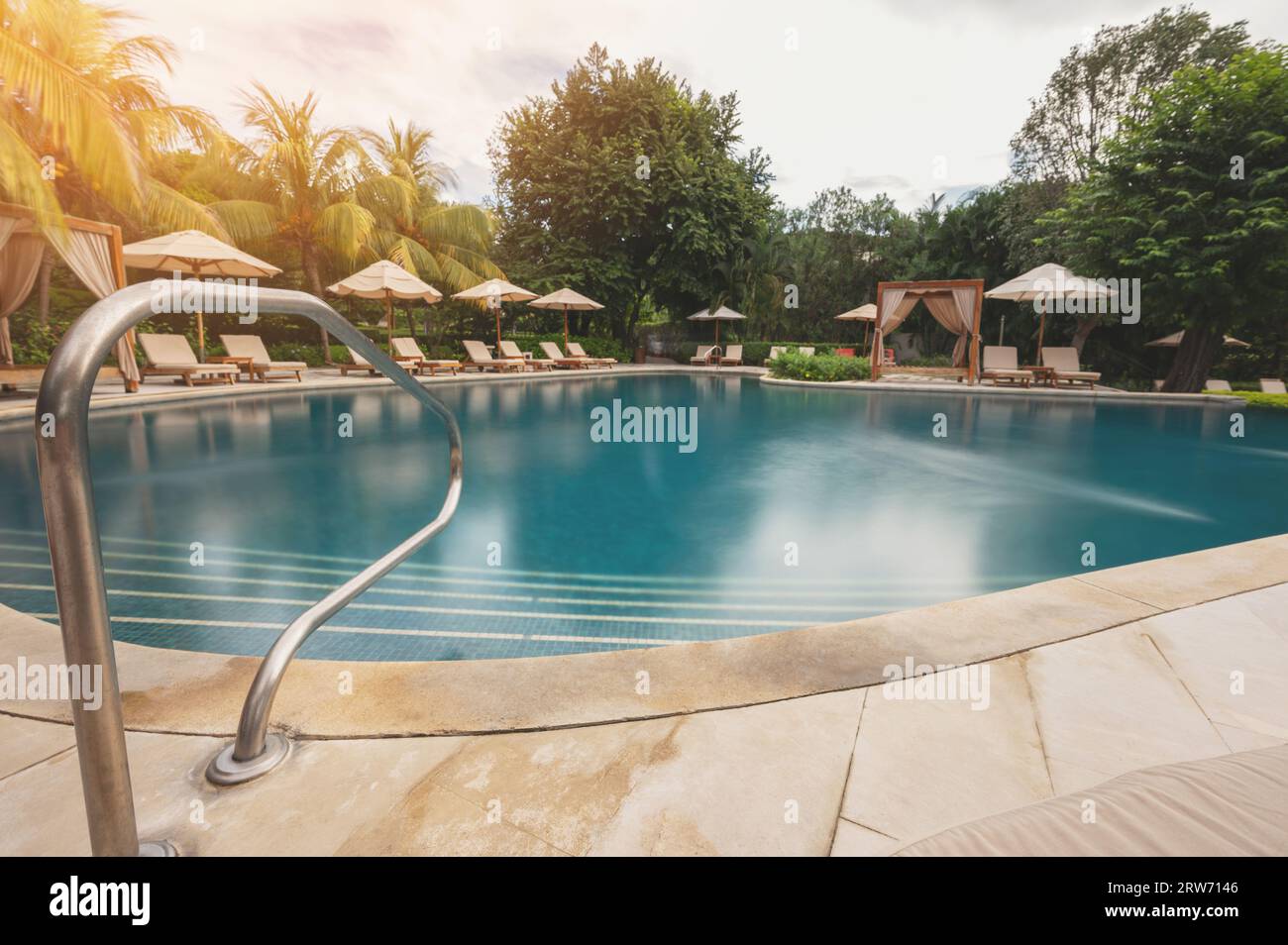 Empty hotel pool outside with green palms trees Stock Photo - Alamy