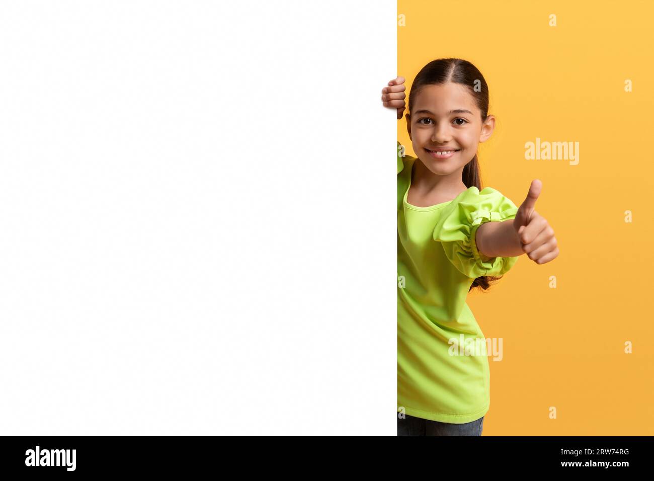 Cute pretty preteen girl by blank advertising placard, thumb up Stock ...
