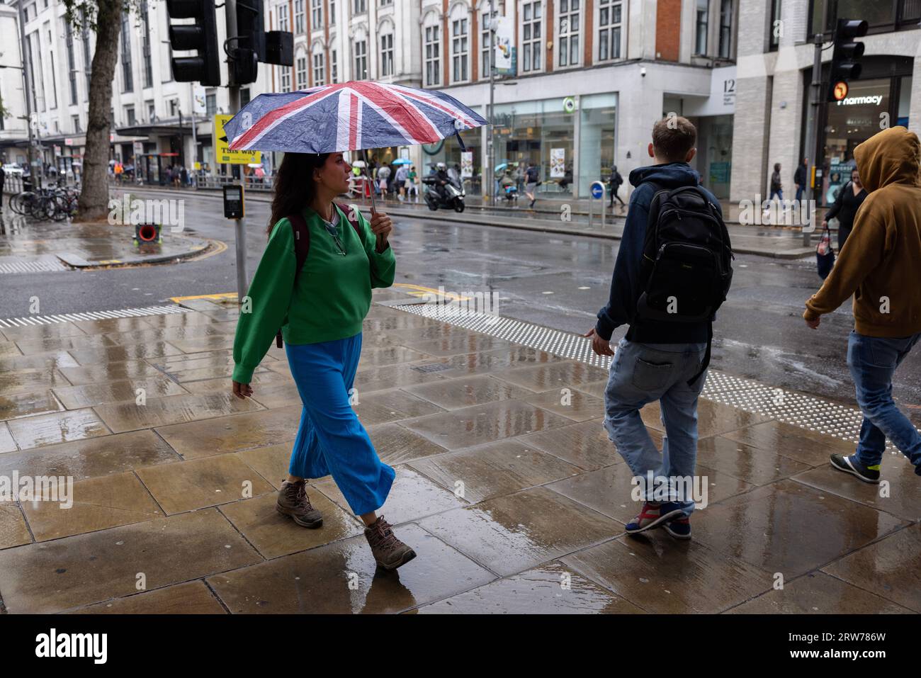 Pedestrians make their way along High Street Kensington in Autumn rain showers, central London ...
