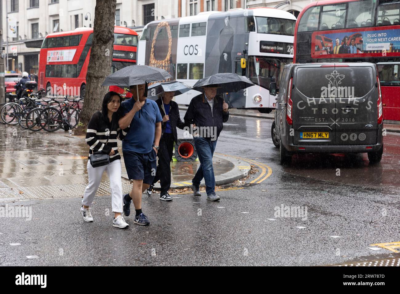 Pedestrians make their way along High Street Kensington in Autumn rain ...
