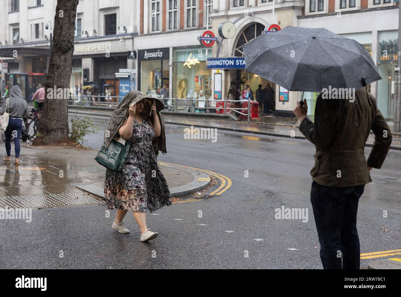 A woman with her umbrella makes her way along High Street Kensington in ...