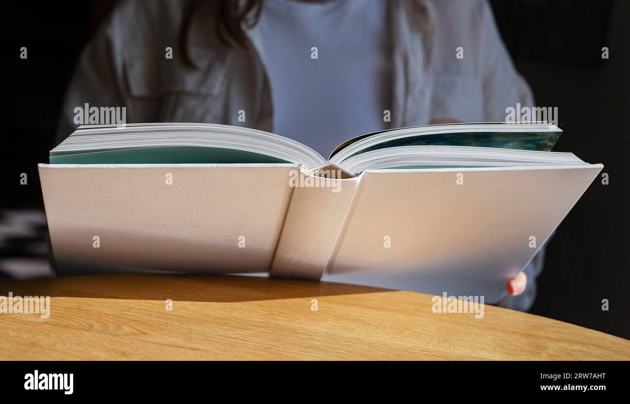 Reading open book, literature at table Stock Photo - Alamy