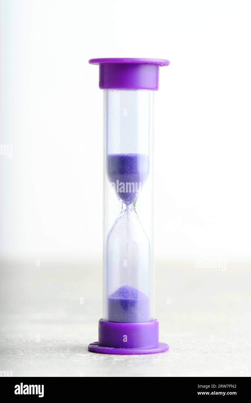 Hourglass for one minute purple on light background Stock Photo - Alamy