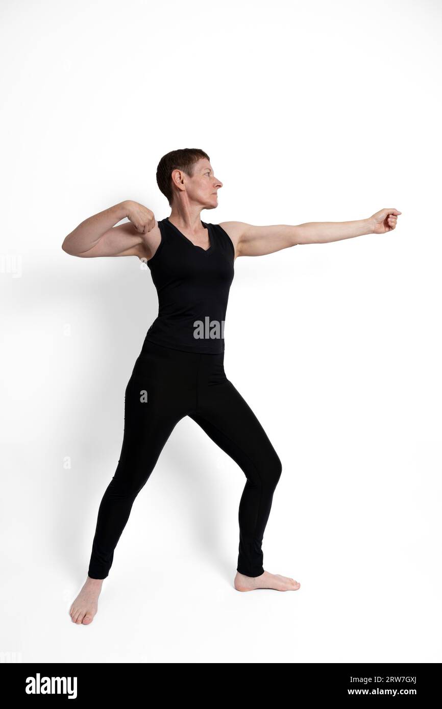 Athletic mature woman dressed in black, miming the sporty gesture of ...