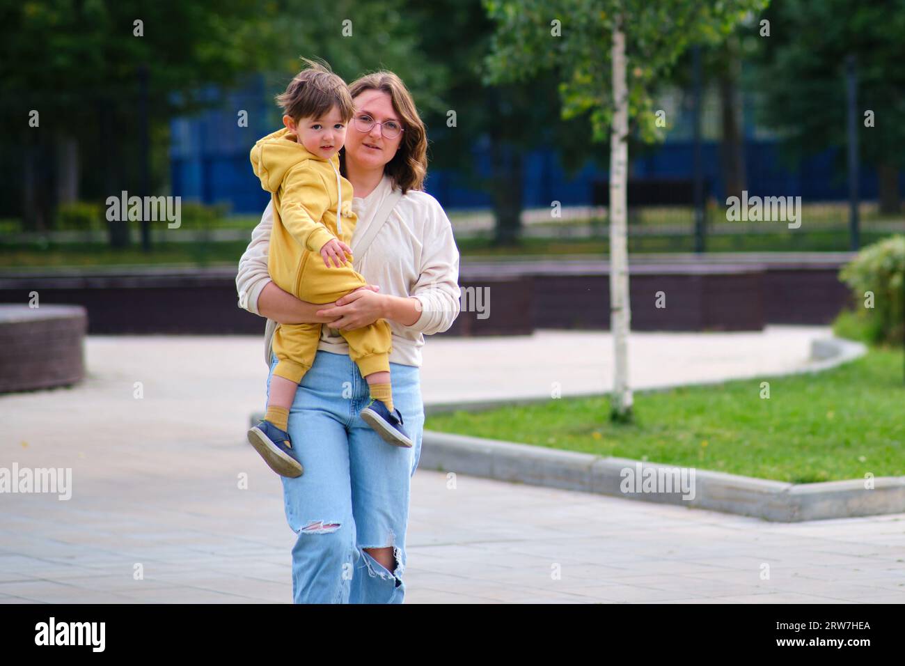 A mother woman carries a toddler baby in her arms during a walk in the ...