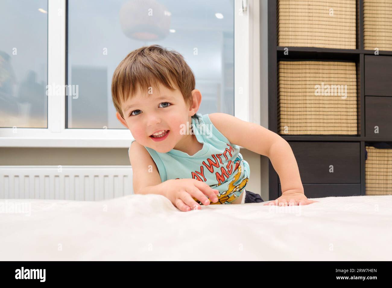 The child is climbing on a high bed, risking an indoor accident. Kid ...