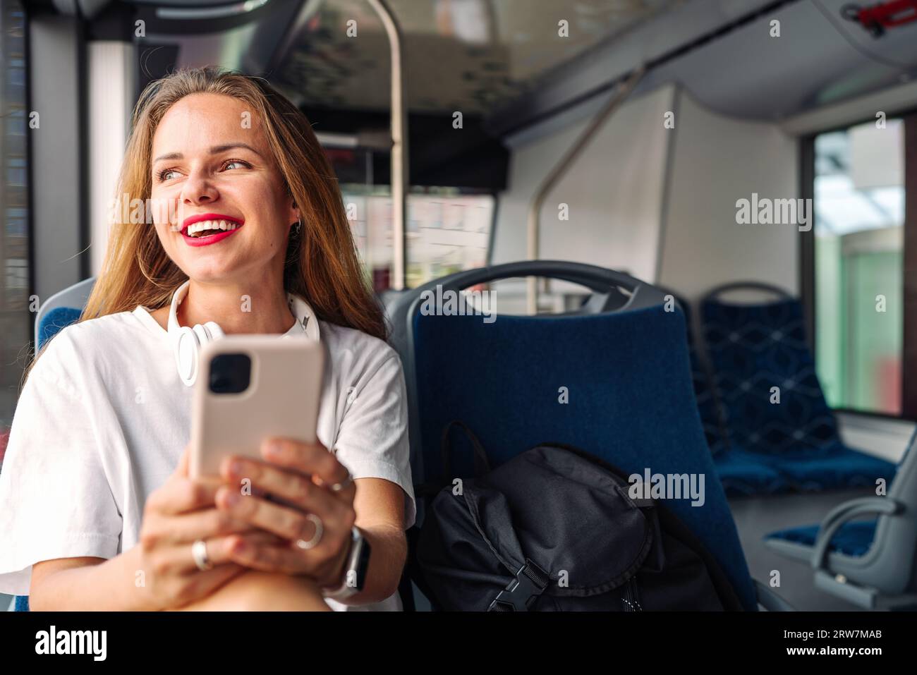 Happy woman laughs and uses a mobile phone while traveling on a public ...