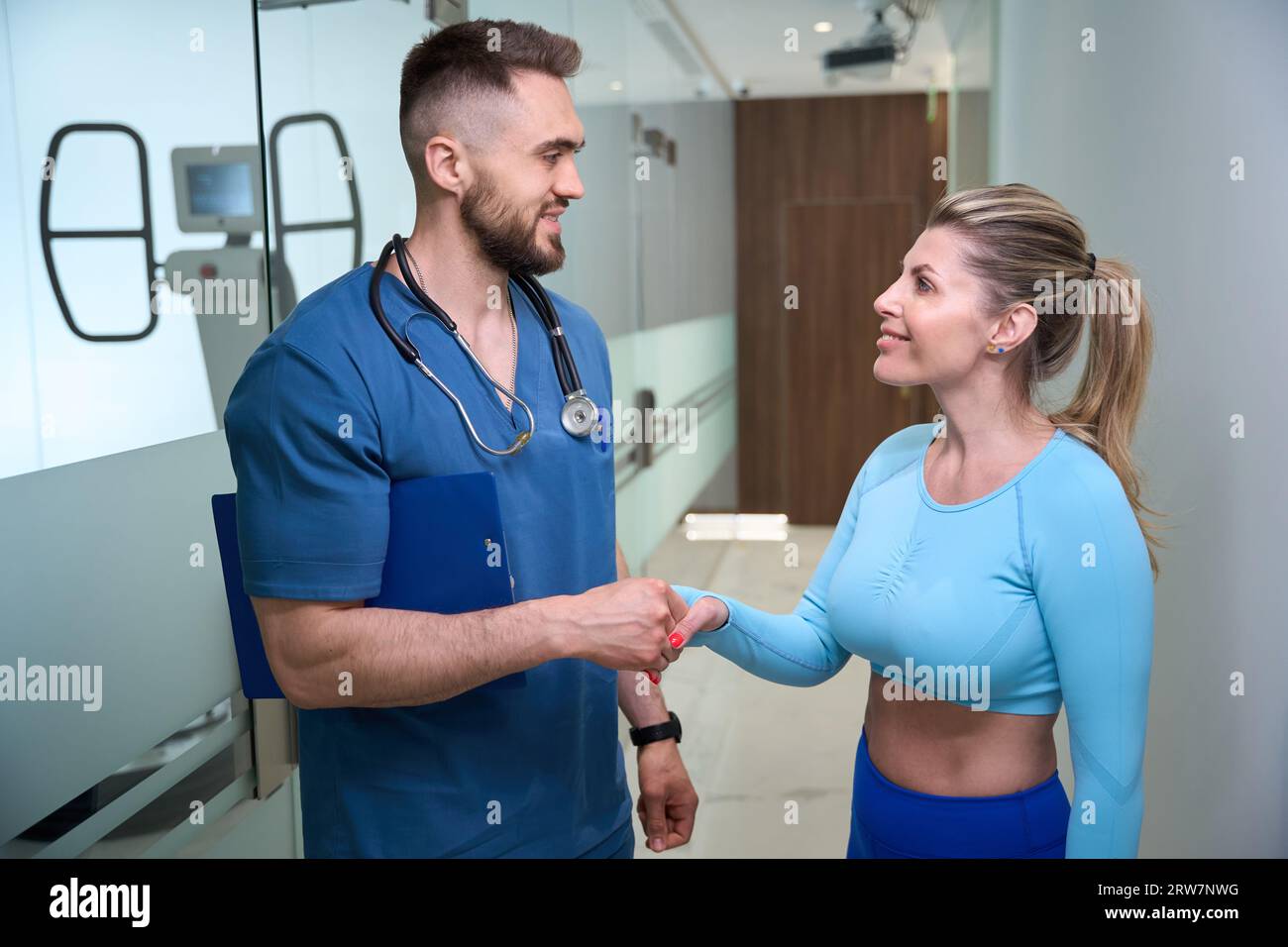Male traumatologist and woman rehabilitation specialist shaking hands ...