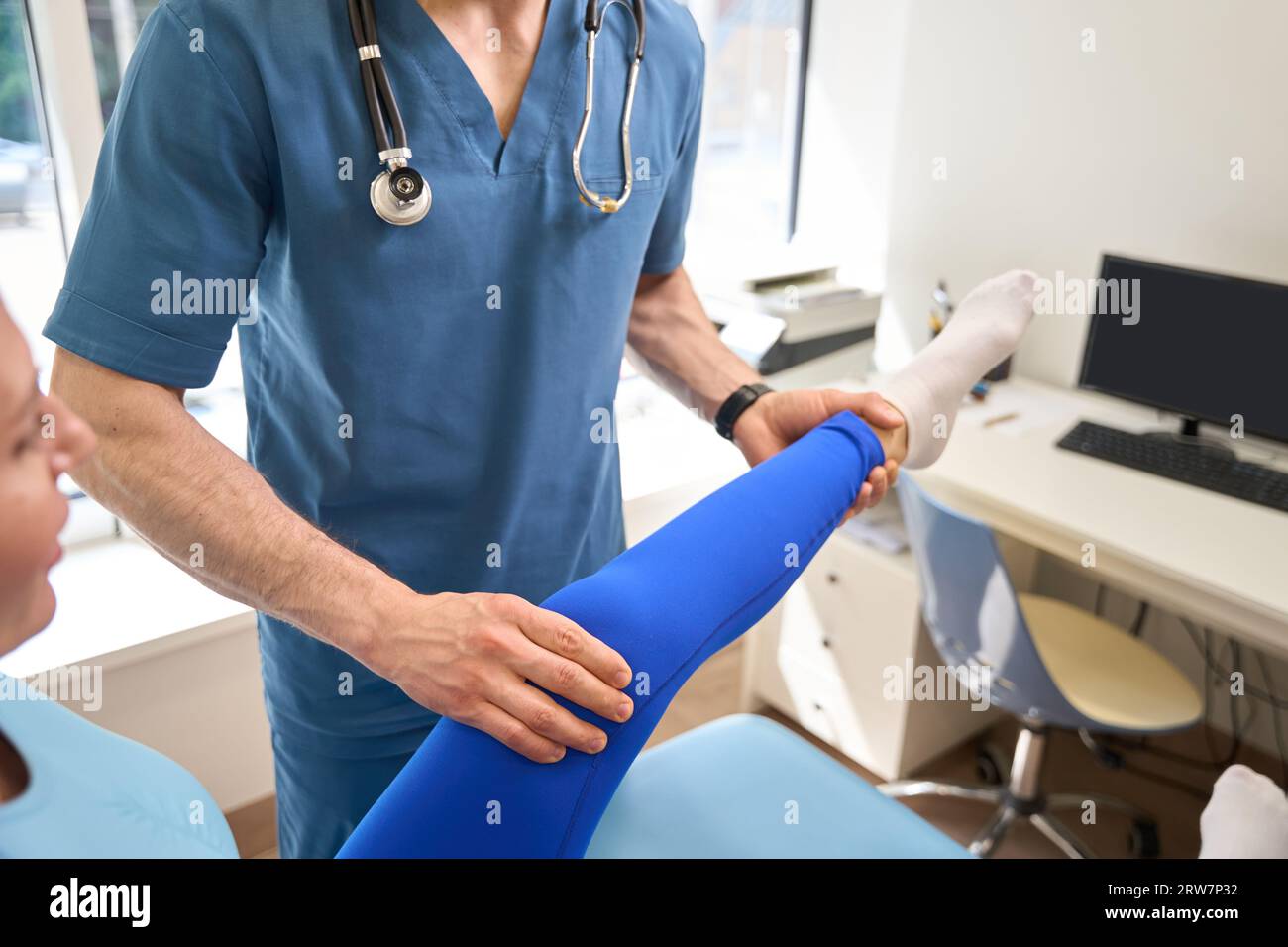 Rehabilitation specialist working with patient leg, straightening and ...