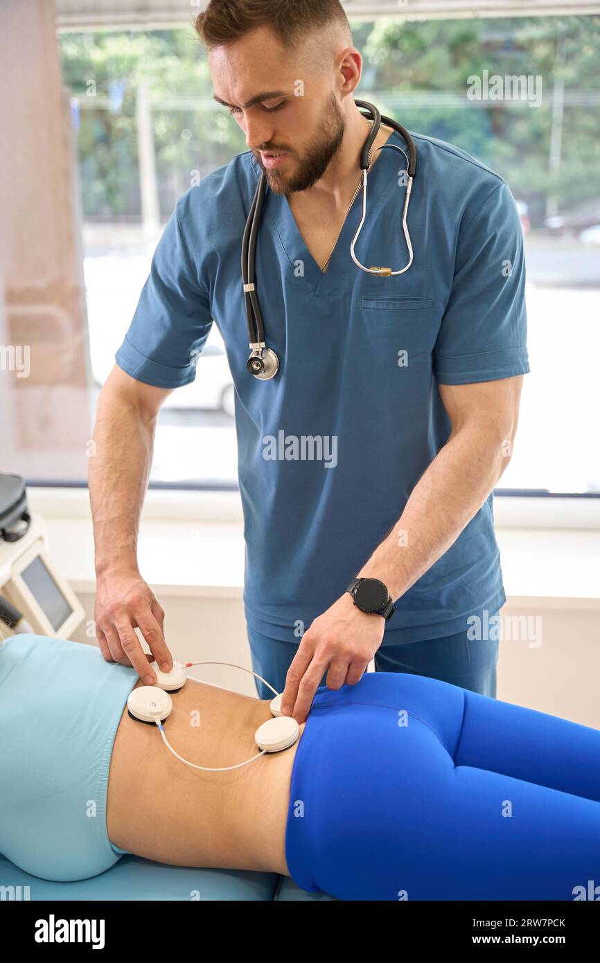 General practitioner using myostimulation to recover sore spine of ...