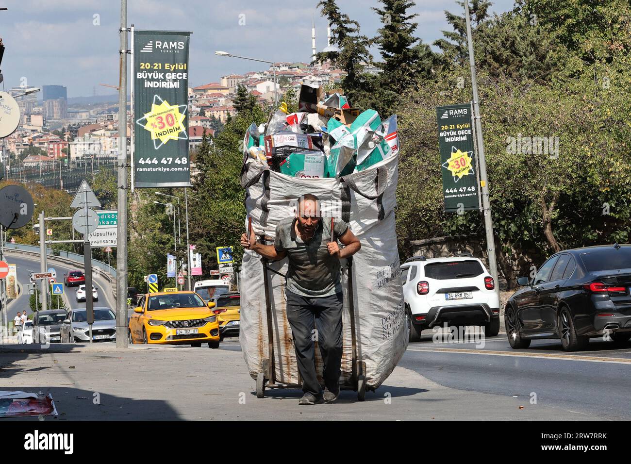 A waste picker hauls their collection of rubbish through the busy roads ...