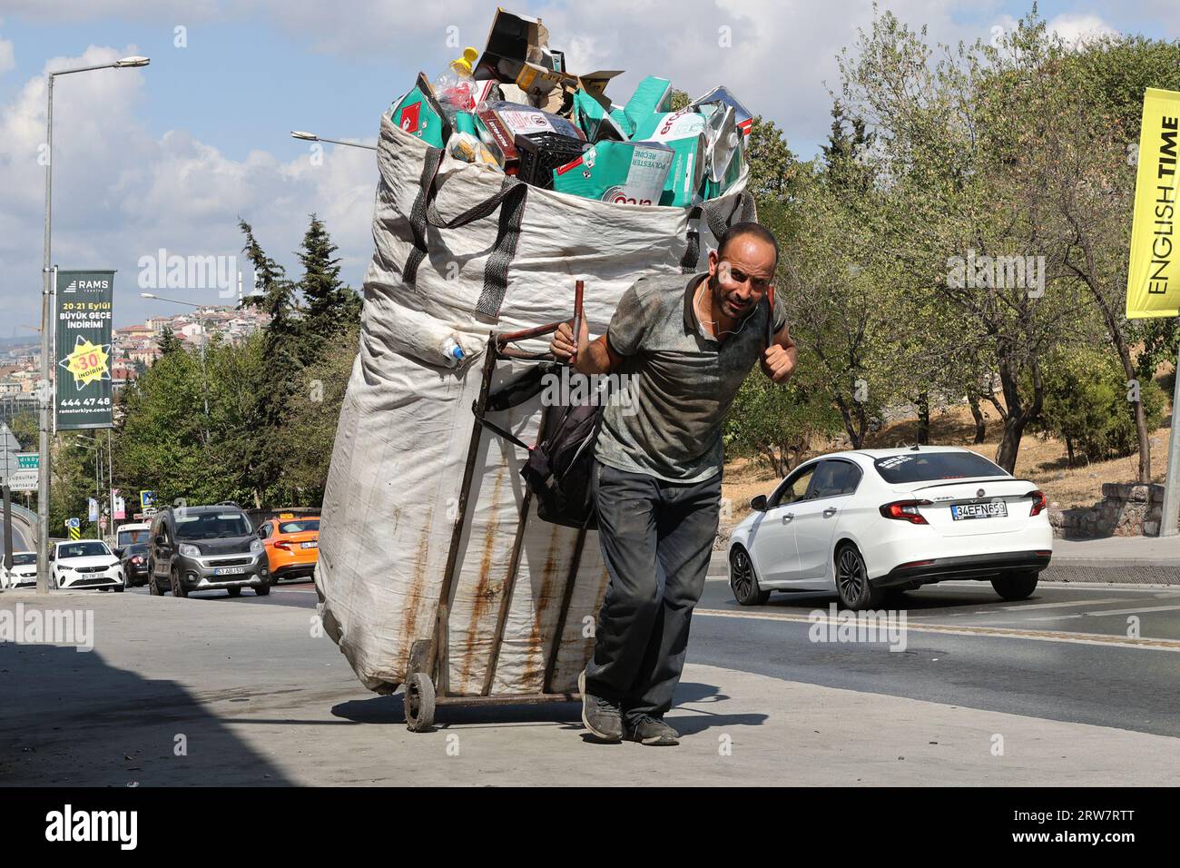 A waste picker hauls their collection of rubbish through the busy roads ...