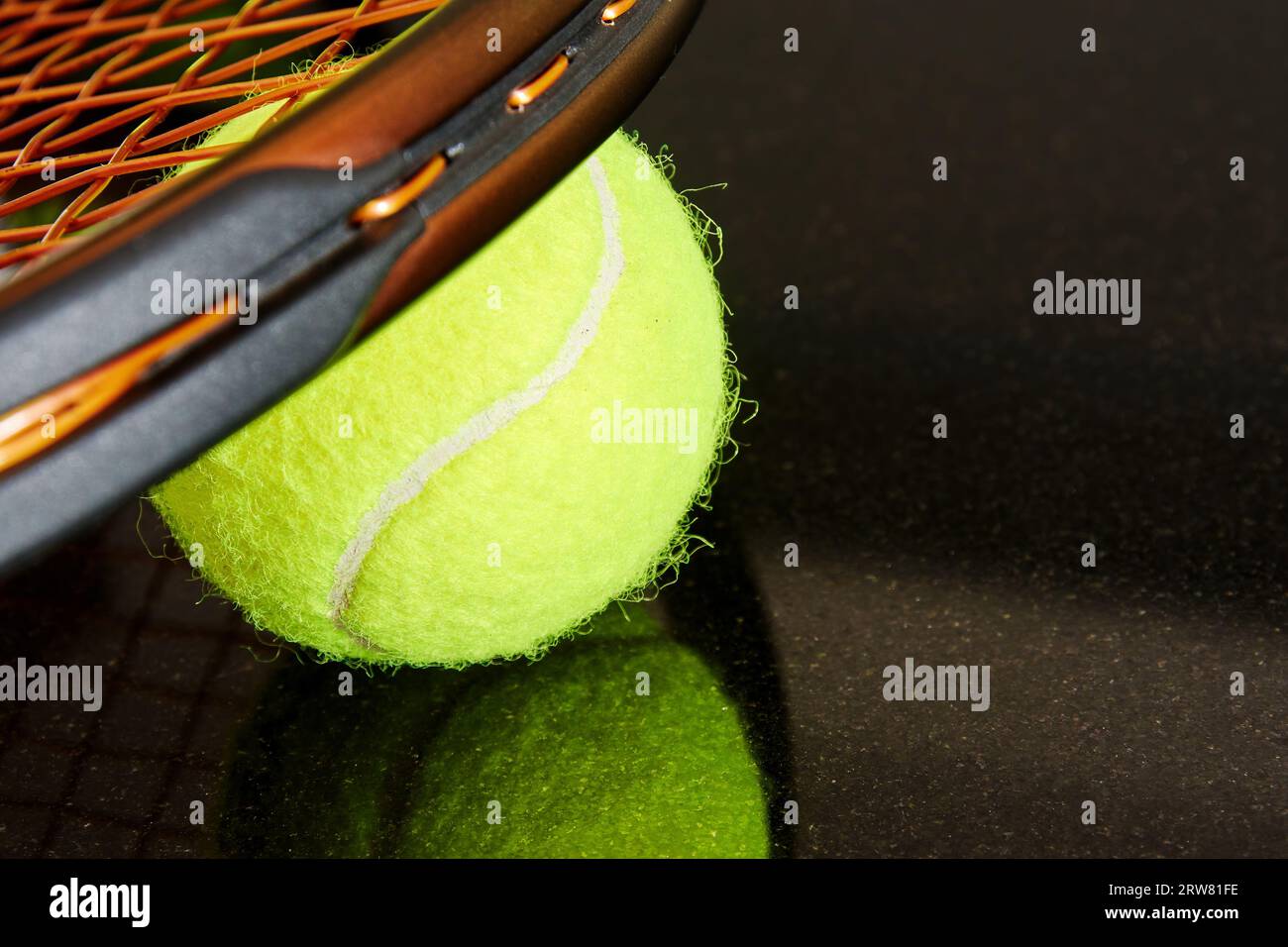Close up view of green tennis ball under the modern pro racquet ...