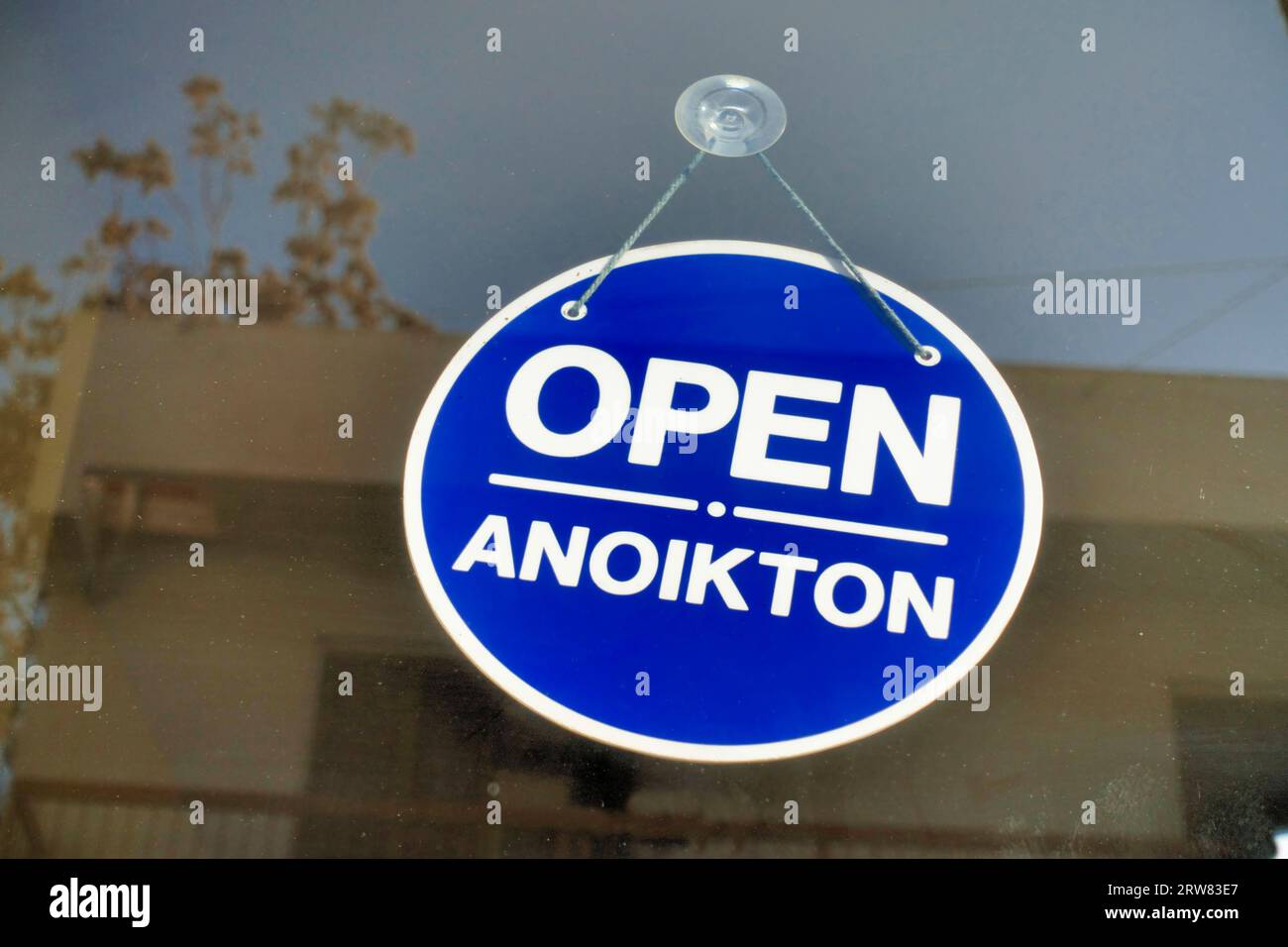 Open sign in Greek and English languages hanging on the door of a shop ...