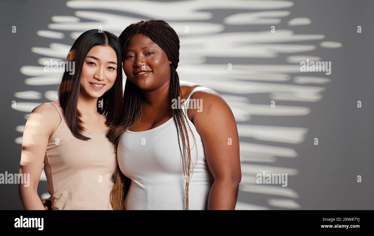Happy diverse ladies hugging and posing in studio, promoting wellness ...