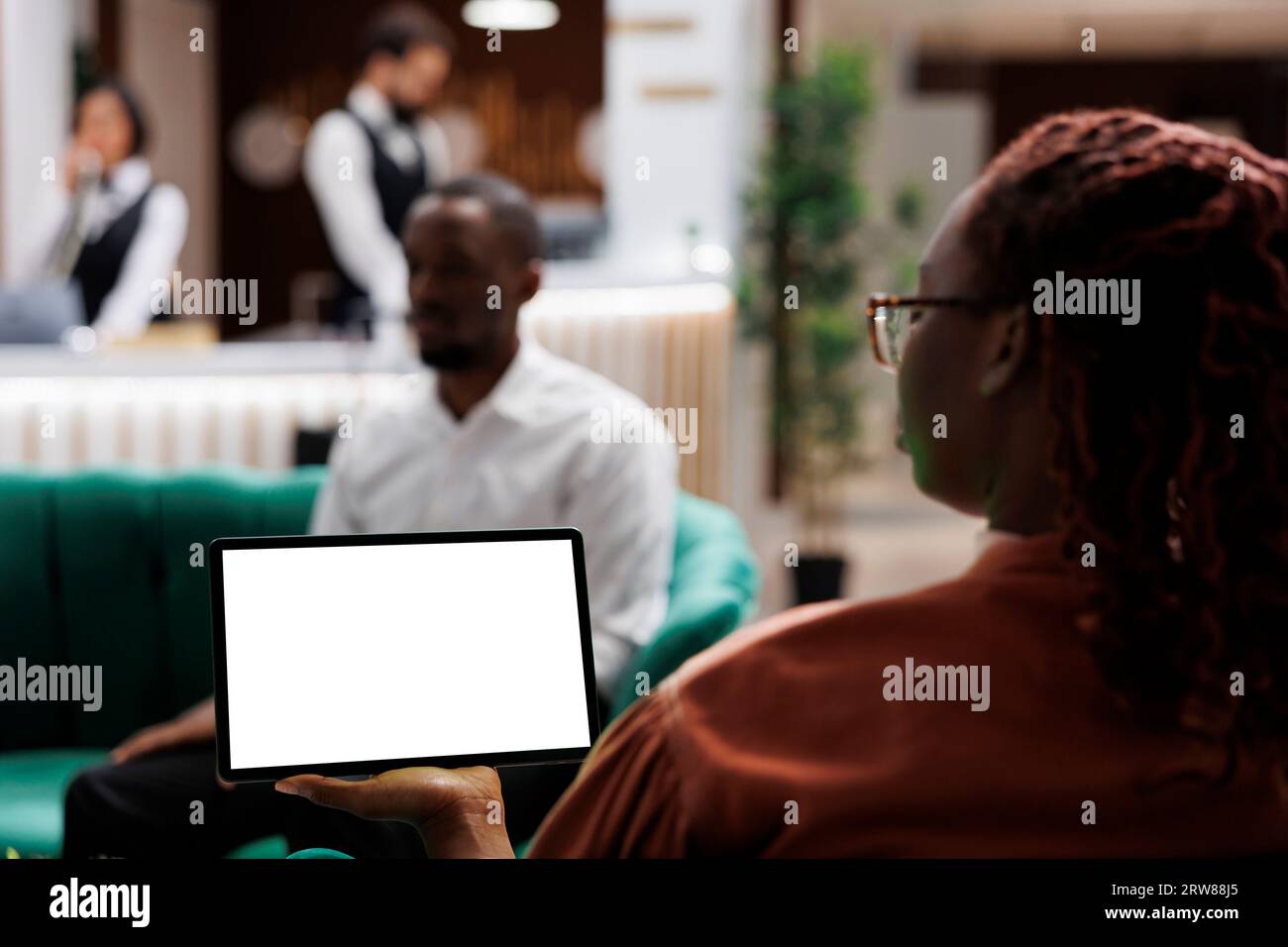 Woman tourist holding tablet in lobby at hotel reception, sitting in ...