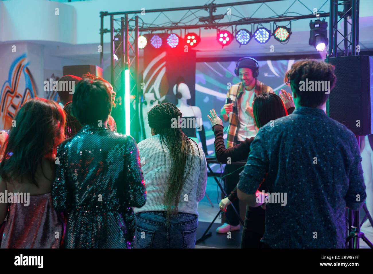 People dancing and partying in nightclub while young man dj performing ...