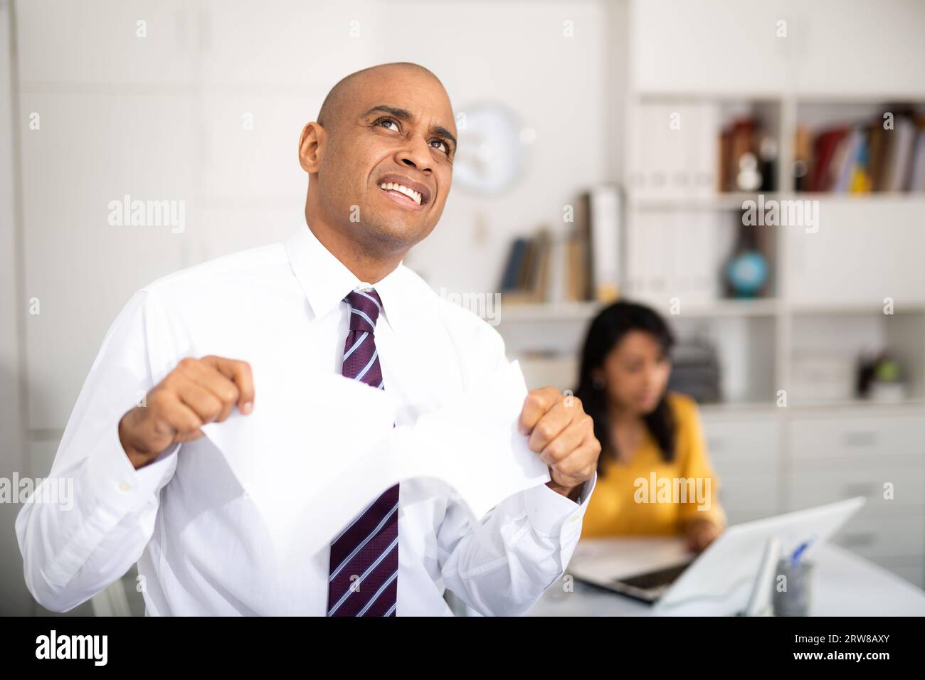 Enraged man tearing piece of paper in office Stock Photo - Alamy
