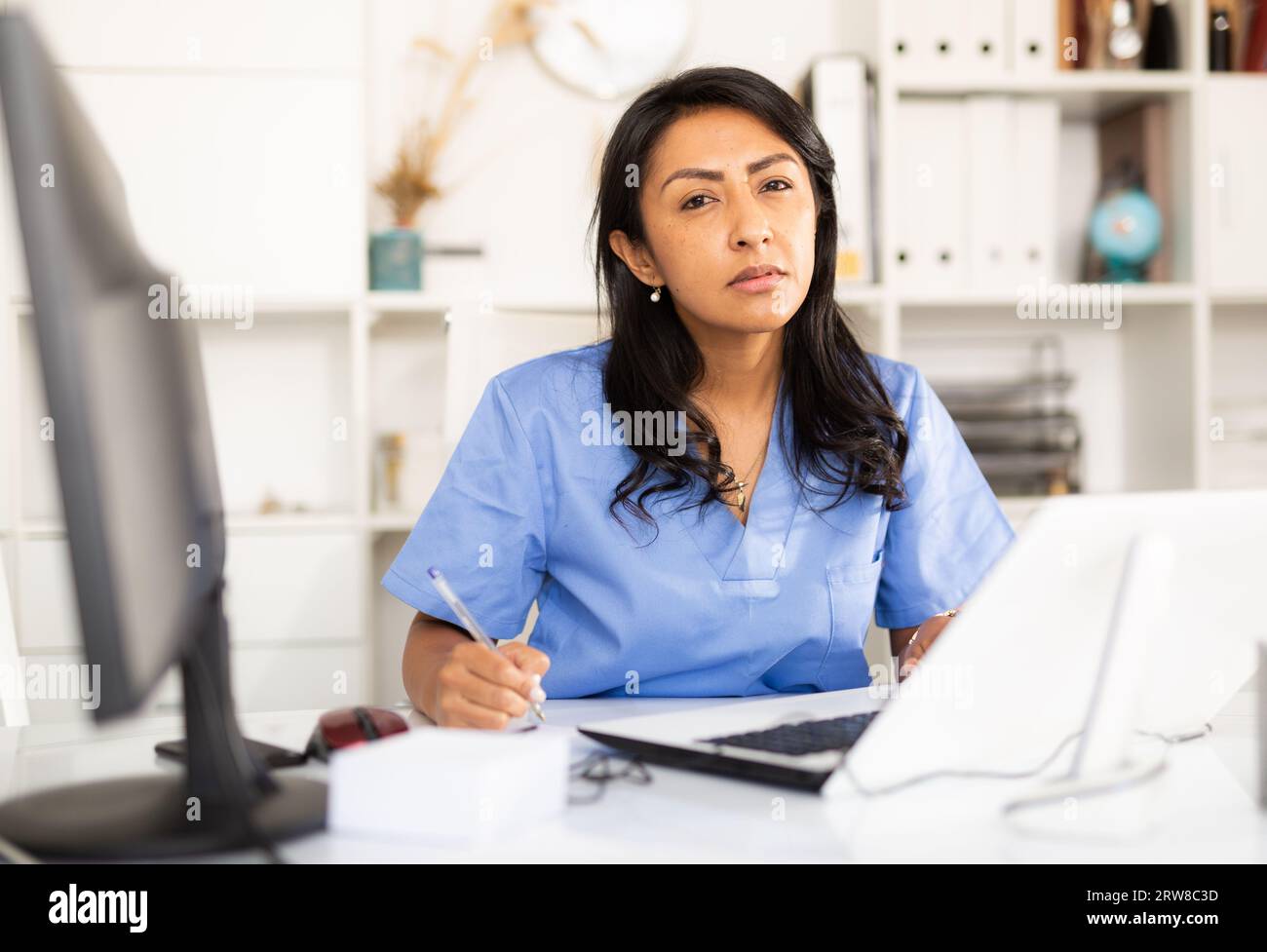 Nurse working on PC in modern private clinic with white walls Stock ...