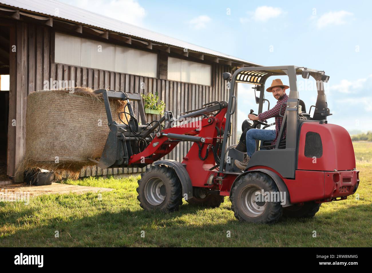 Farmer in loader transporting hay on farm. Agriculture equipment Stock ...