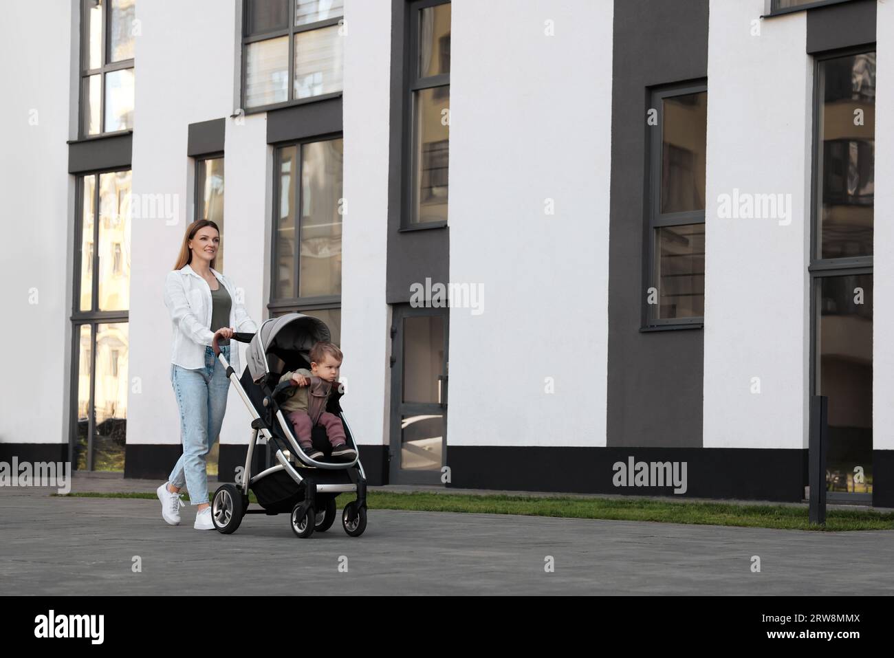 Happy nanny with cute little boy in stroller walking outdoors Stock ...