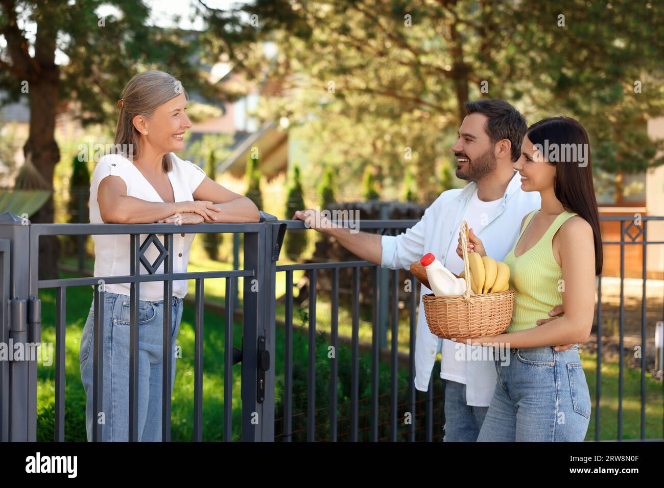 Friendly relationship with neighbours. Young couple with wicker basket ...