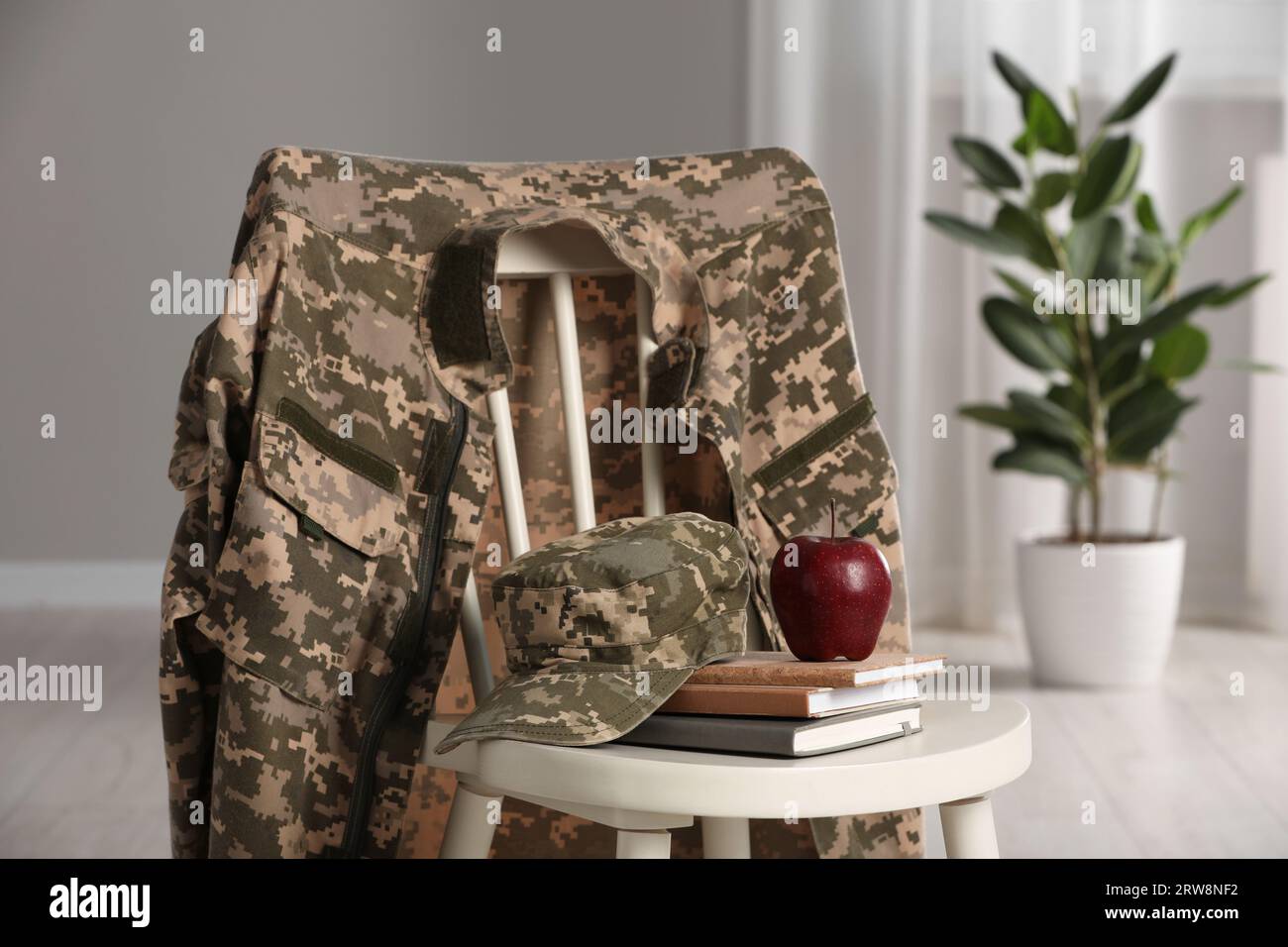 Chair with soldier uniform, notebooks and apple indoors. Military ...