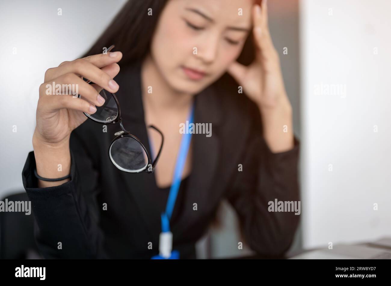 Close-up image of a stressed Asian businesswoman taking off her glasses ...