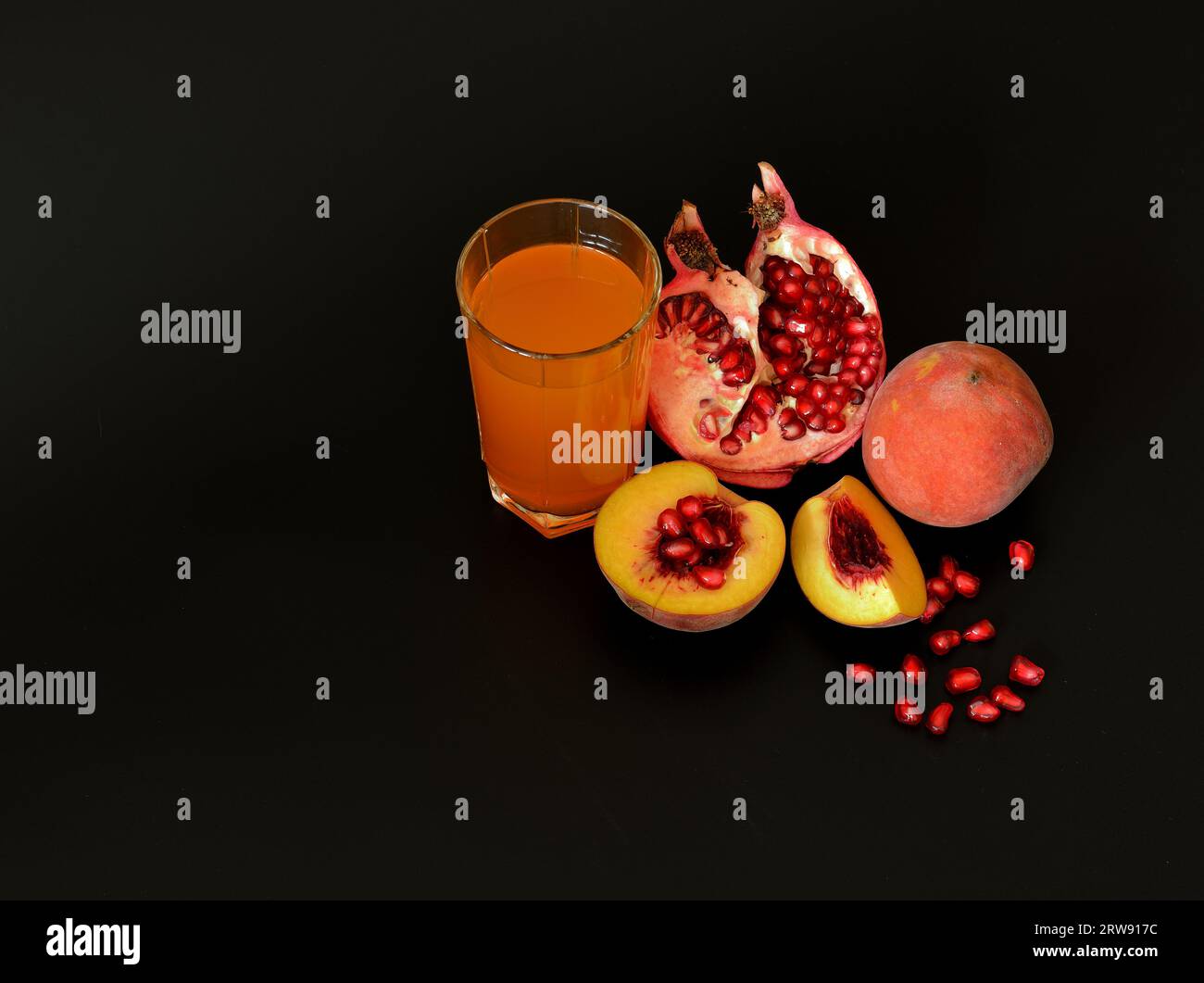 A tall glass of freshly squeezed juice on a black background, next to ...