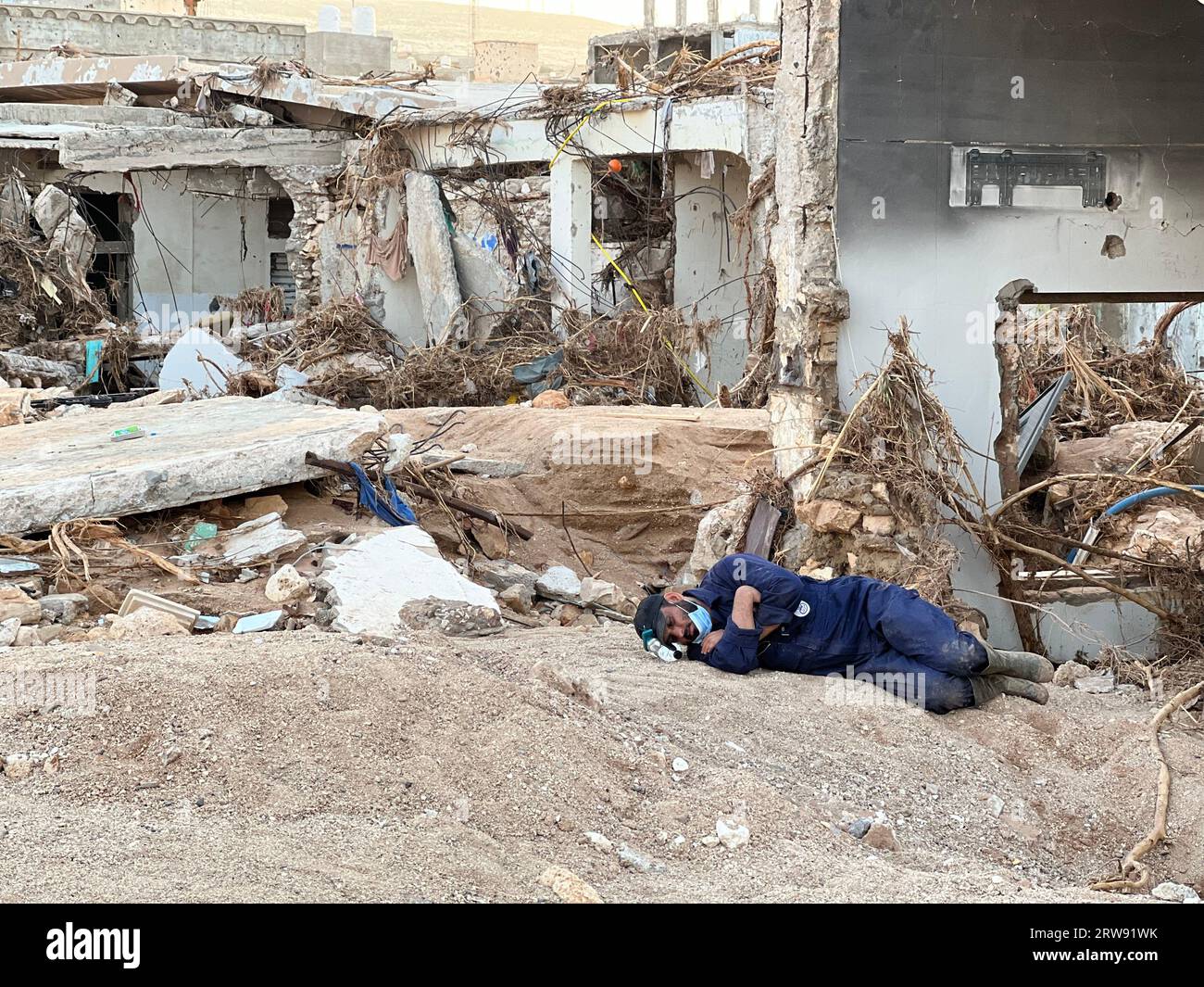 Derna. 17th Sep, 2023. A rescuer takes a rest on a damaged building in ...