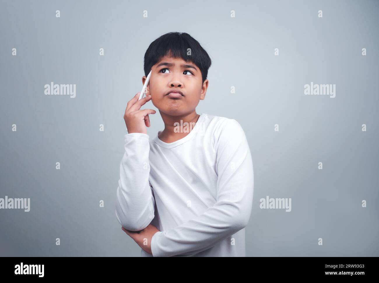 A boy in a white shirt is holding a white pen on a white background ...