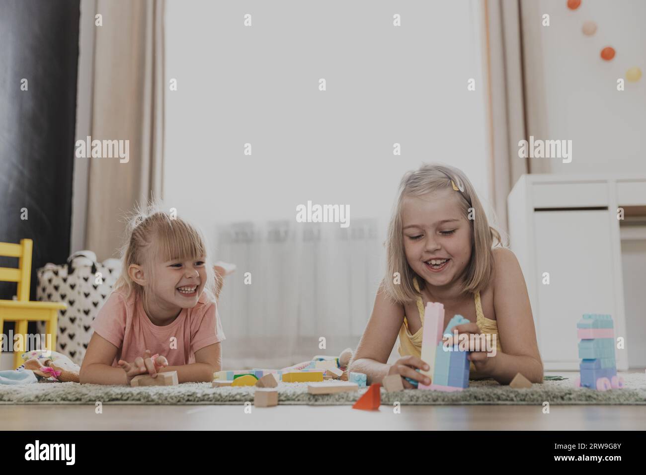 Children playing with colorful toys. Kids sitting on carpet at home ...