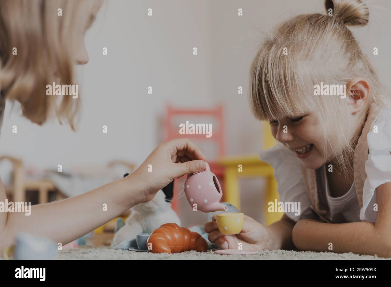 Close-up of female children playing tea party with colorful toy set ...