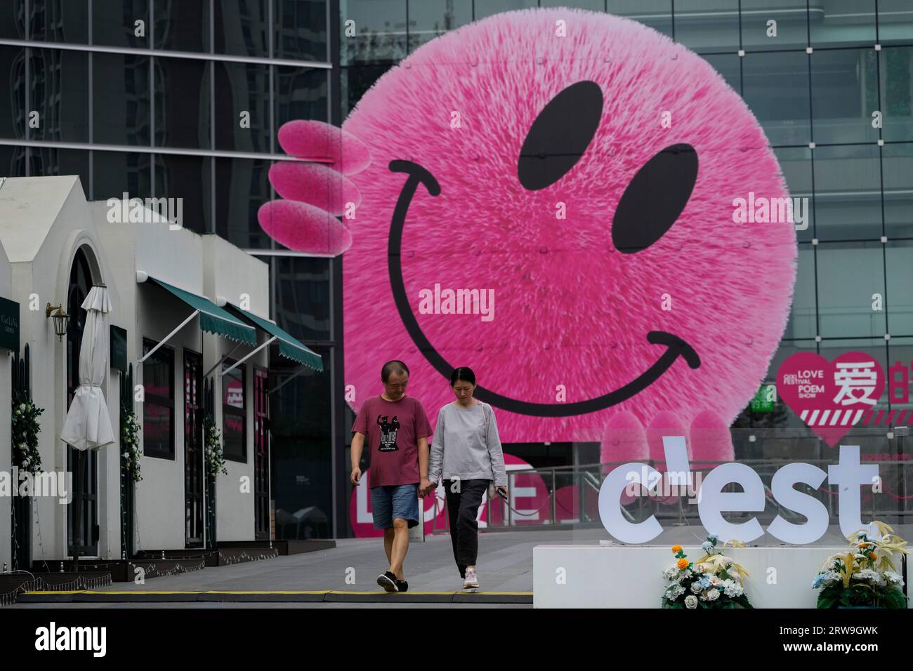 A couple walk by promotion booths setup outside a shopping mall in ...