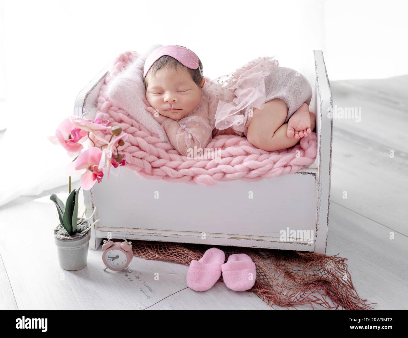 Adorable newborn baby girl sleeping in tiny bed on knitted blanket. Cute infant child kid in ...
