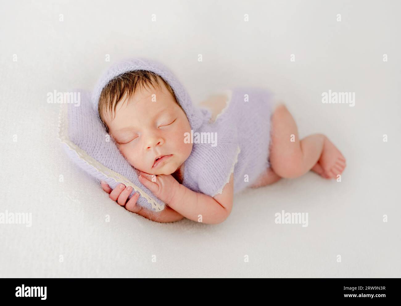 Adorable newborn baby girl sleeping on pillow. Cute infant child kid in knitted dress napping ...