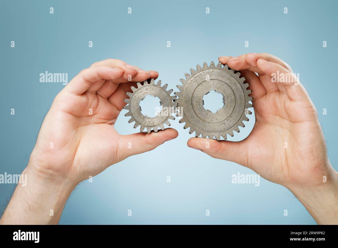 Man holding two different sizes metallic cog gear wheels in his hands ...