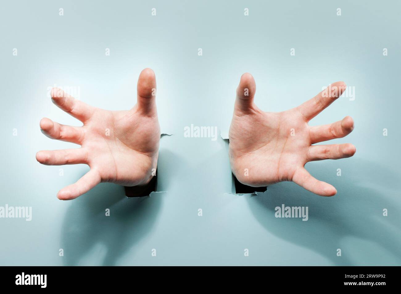 Strange hands coming through holes in a blue cardboard Stock Photo - Alamy