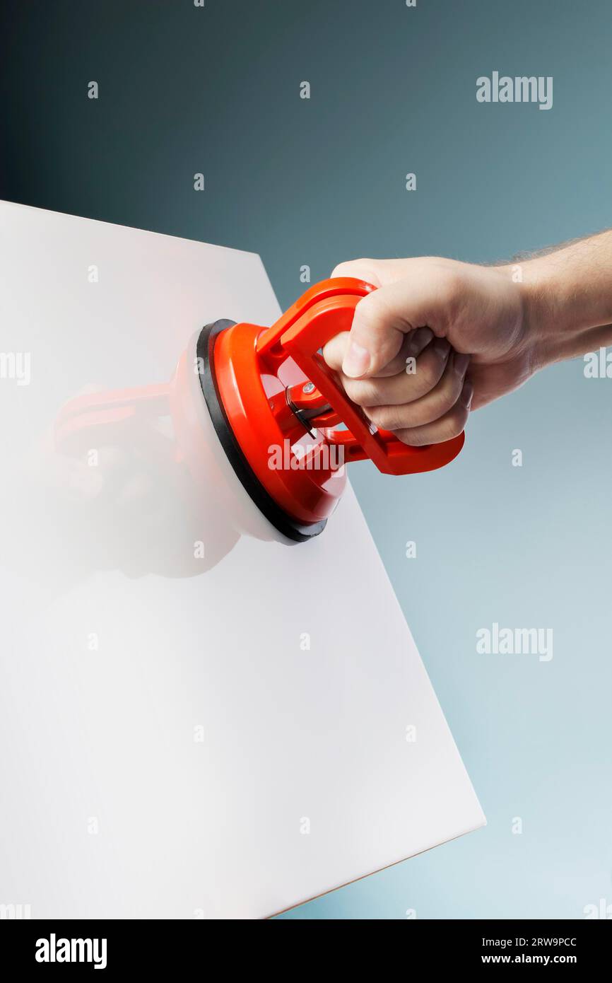 Man lifting a white ceramic tile using a vacuum suction cup tool aka ...