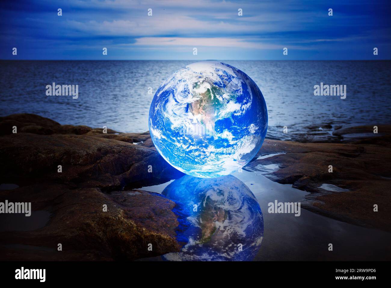 Conceptual image of a Glowing earth in a puddle at sea. Earth image ...